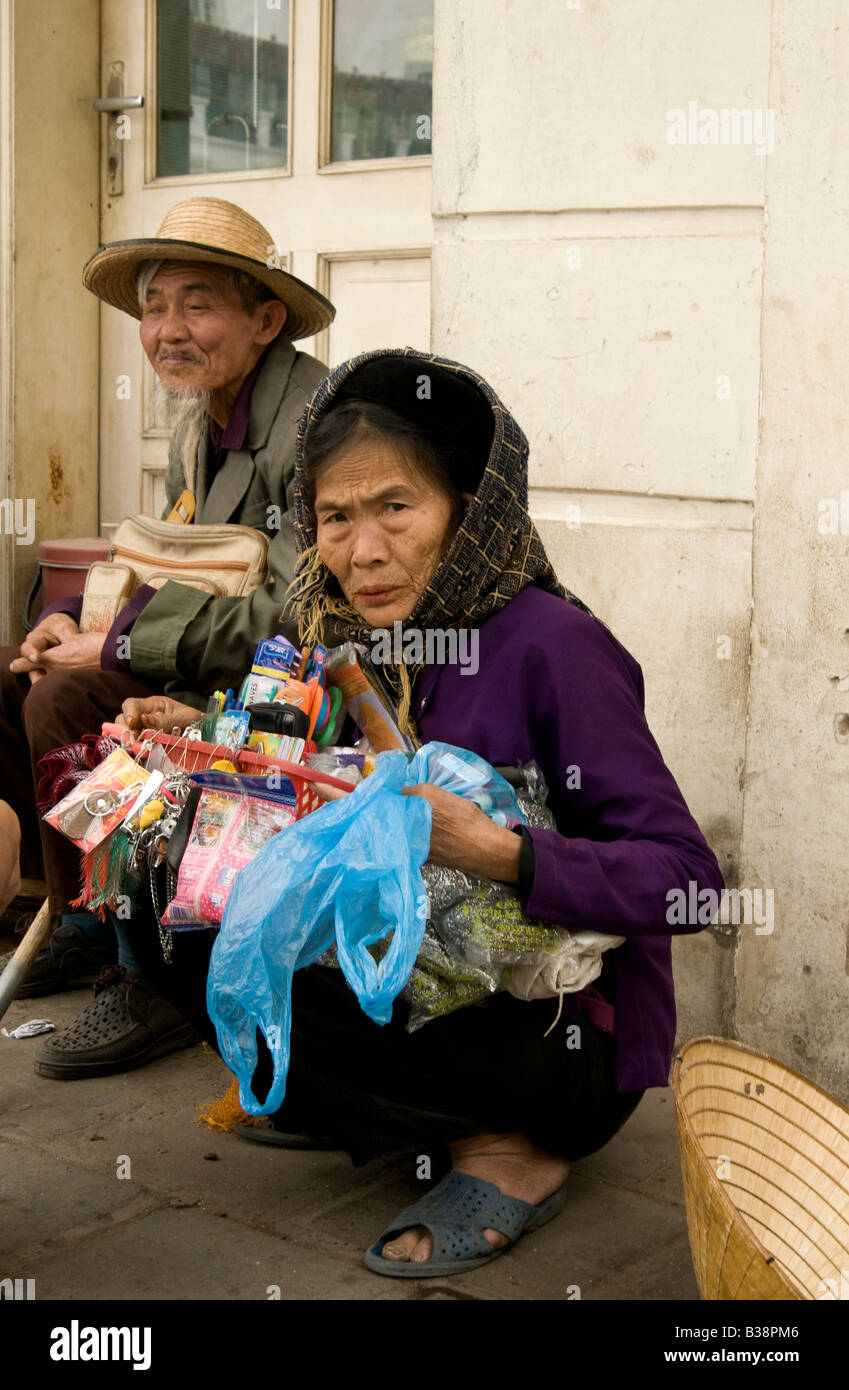 An old Vietnamese woman stares at the viewer while squatting on the ...