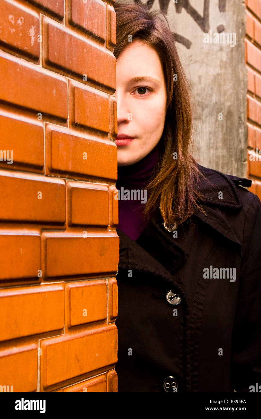Woman looking behind a brick wall Stock Photo - Alamy