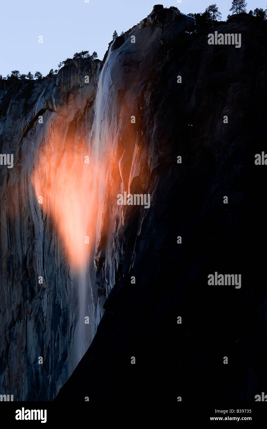 Mist from Horsetail Falls is illuminated by warm setting sun light in ...