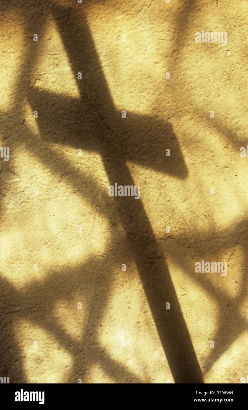 Shadow of crucifix cast onto cream painted rough wall with projection ...