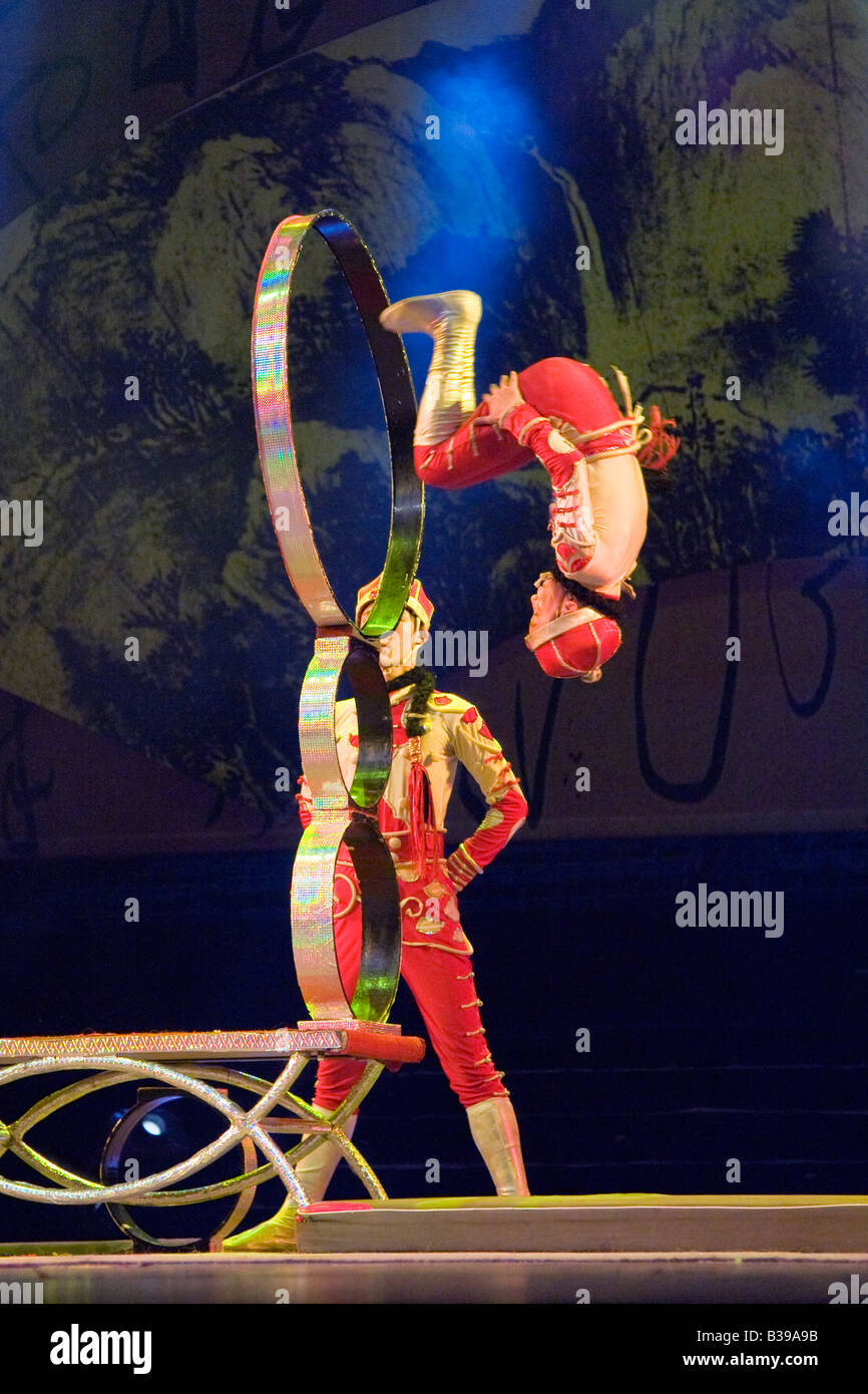 Acrobat in mid air jumps through hoop and sumersaults at acrobatics ...
