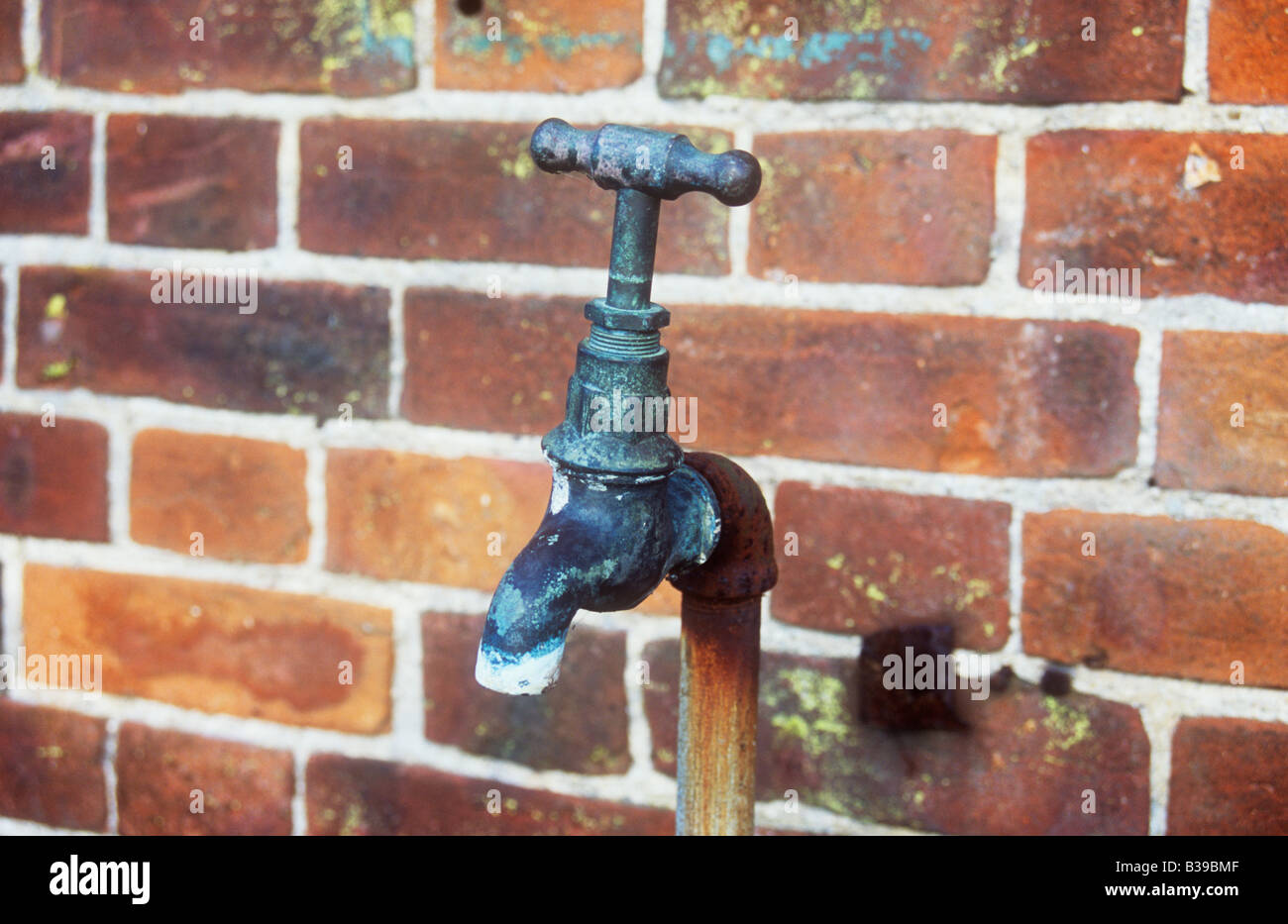 Close up of old fashioned stained outside tap fixed to rusting pipe ...