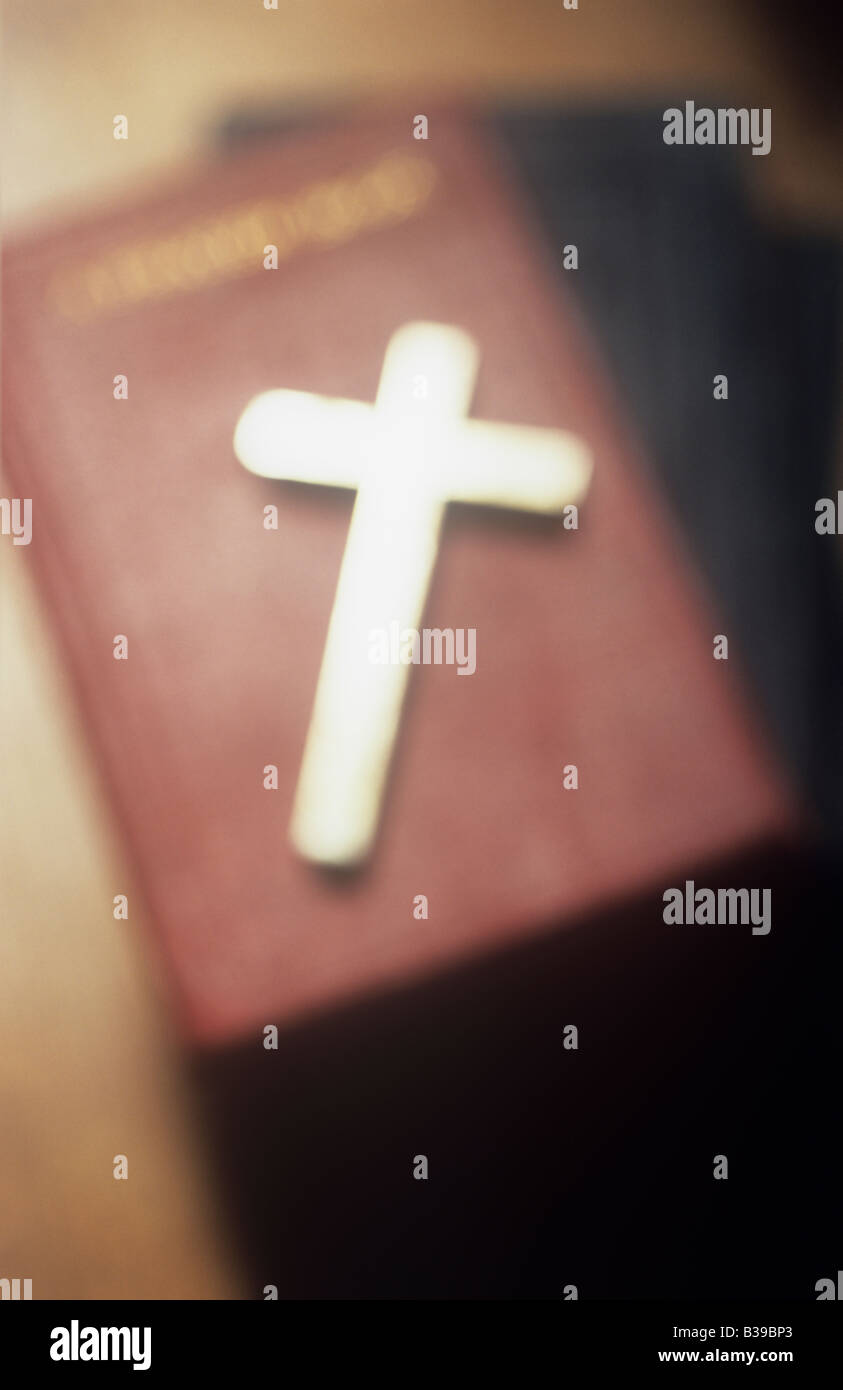 Impressionistic gold or silver crucifix lying on books on shelf or ...