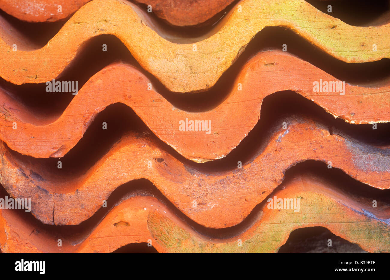 Close up of end of stack of red clay pantiles or curved roofing tiles ...