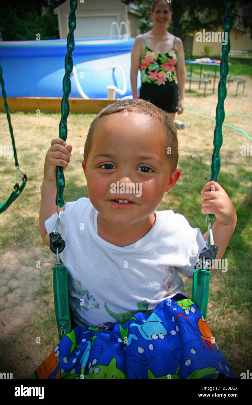 Young Latino boy playing outside on a swing Stock Photo - Alamy