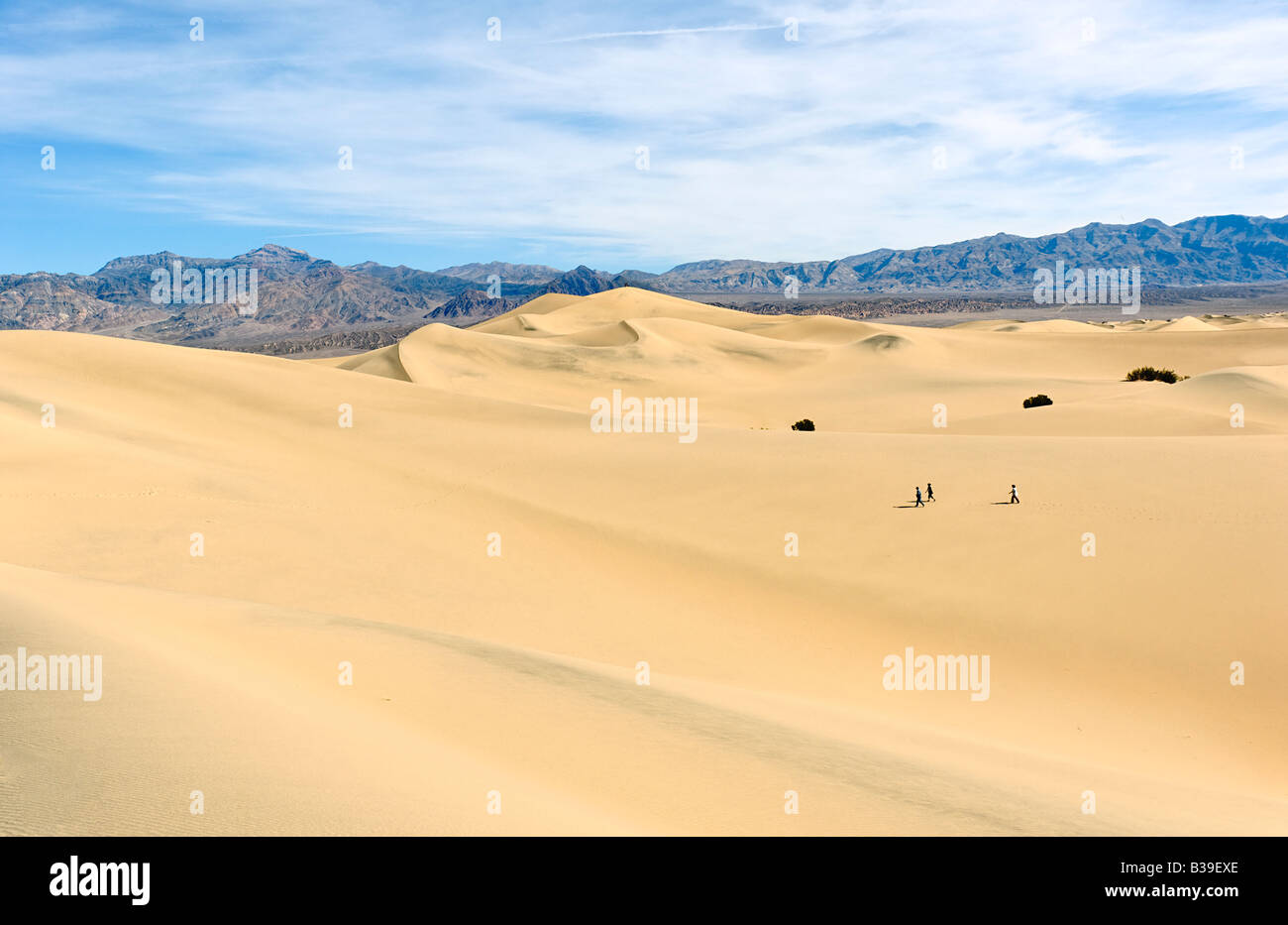 Three people walking across the sand dunes in Death Valley Stock Photo ...