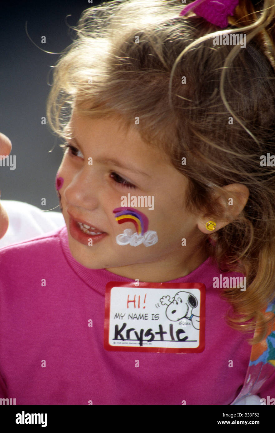Little girl with painted face wears name tags as she plays at special ...