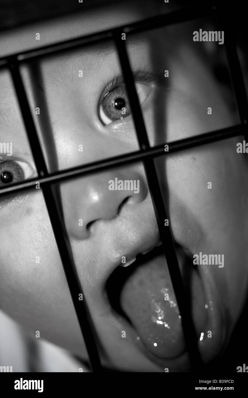Dramatic baby behind a baby gate portrait with deep shadows Stock Photo ...