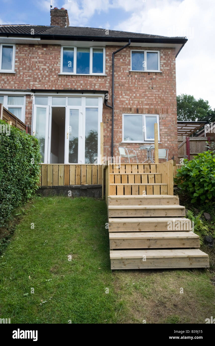 house with wooden decking and patio leading to garden Stock Photo - Alamy