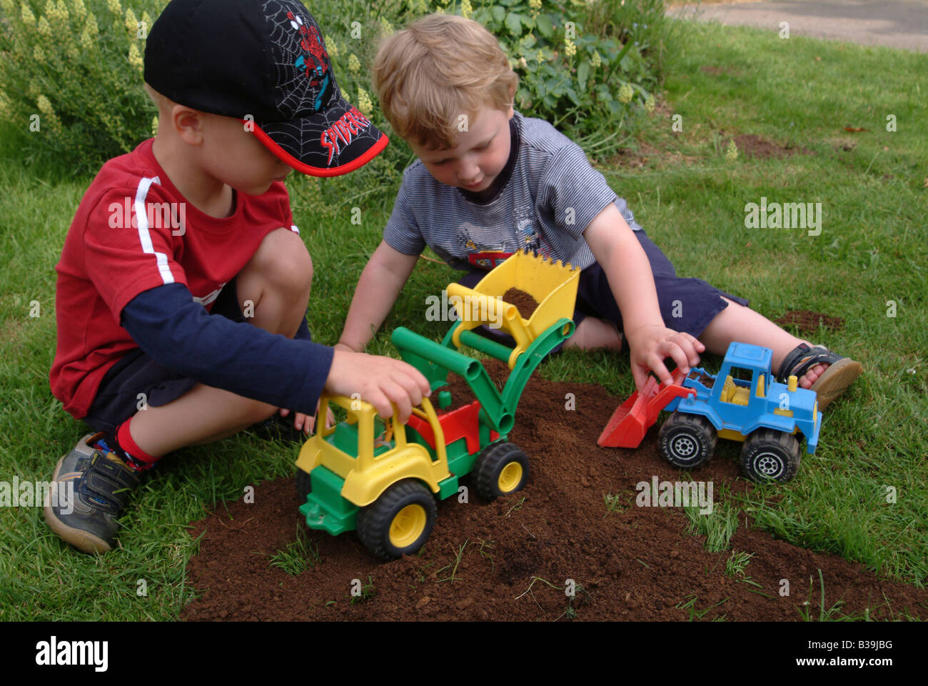 Two boys playing with soil and toy diggers Stock Photo - Alamy
