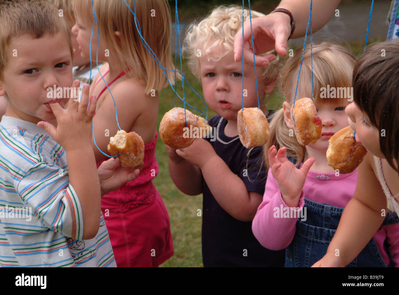 Children eating doughnuts off a string Stock Photo - Alamy