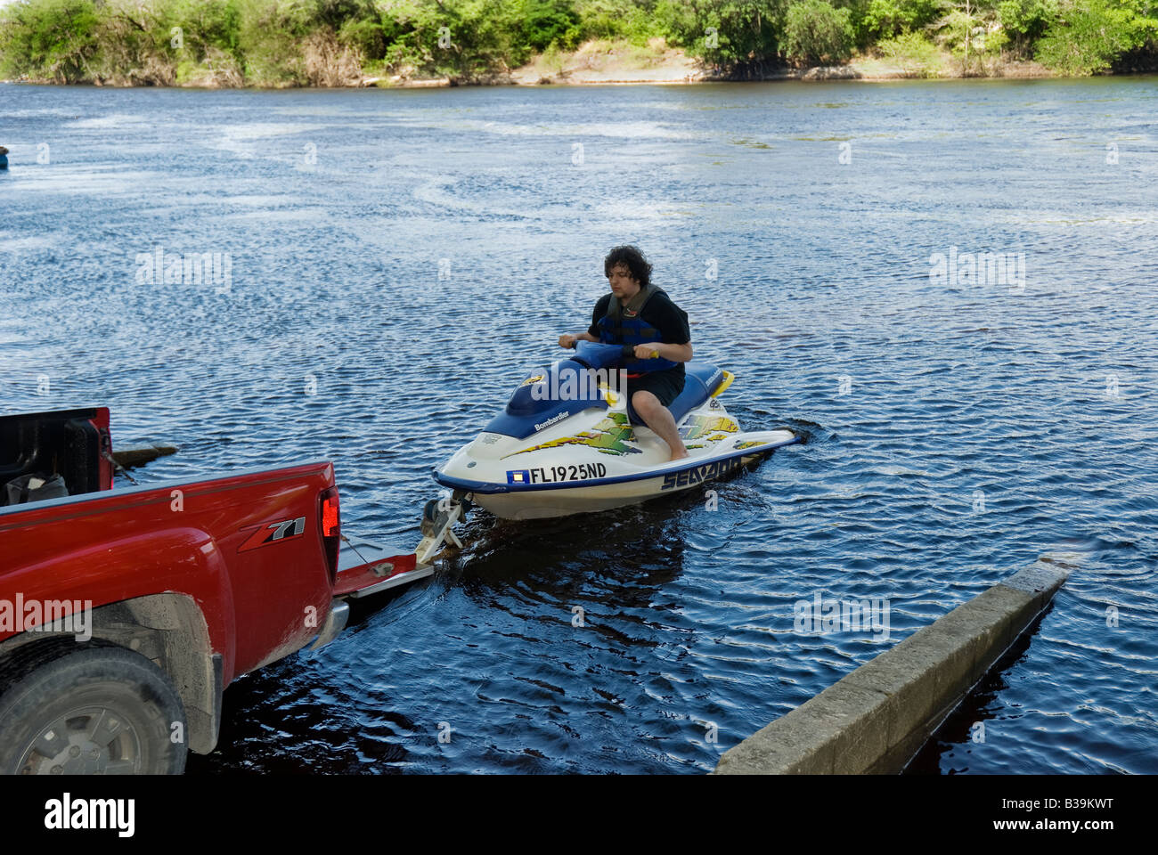 jet skier launching his craft off trailer behind pickup truck along the ...