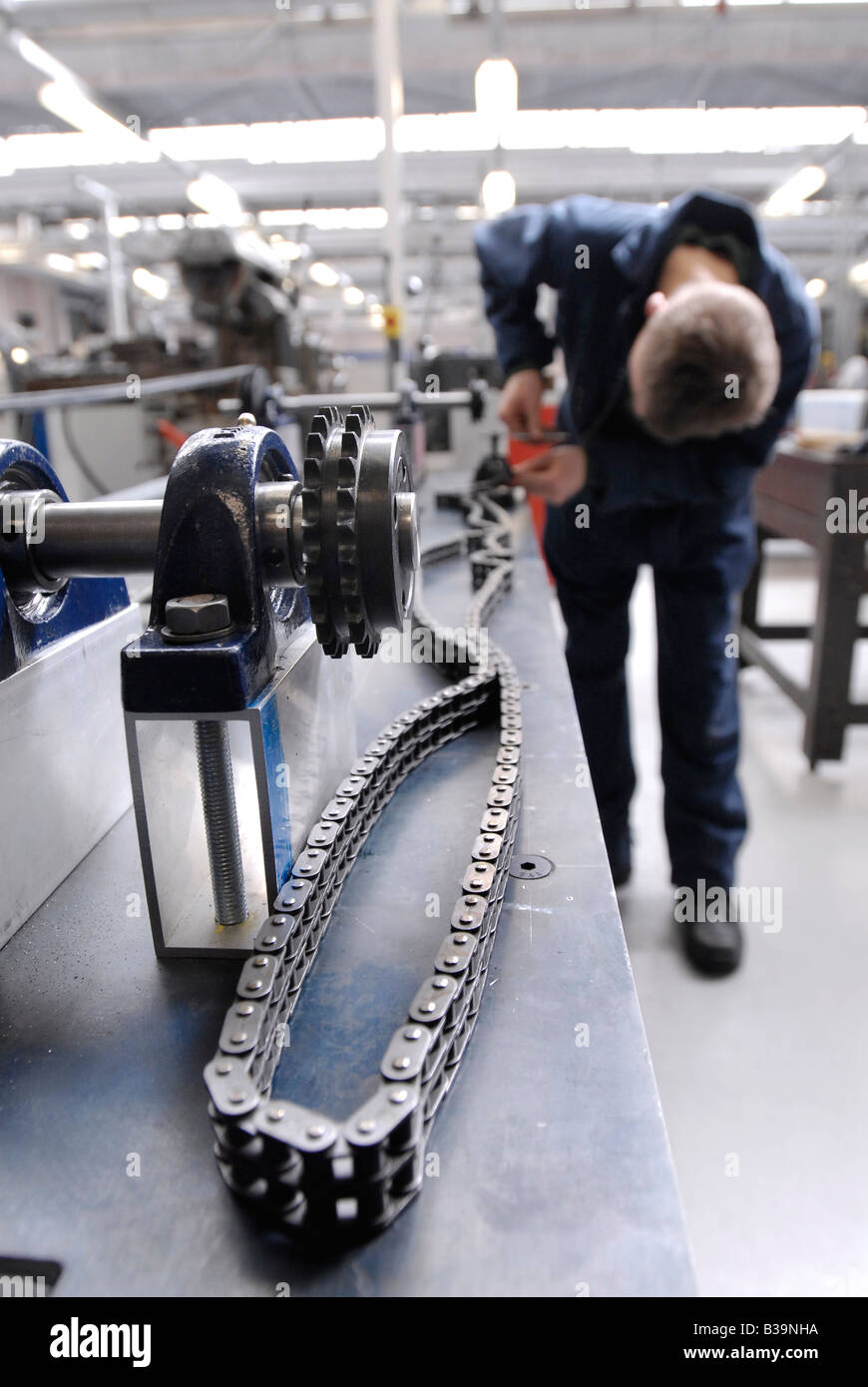 Engineering apprentice repairing a chain drive belt in an engineering ...