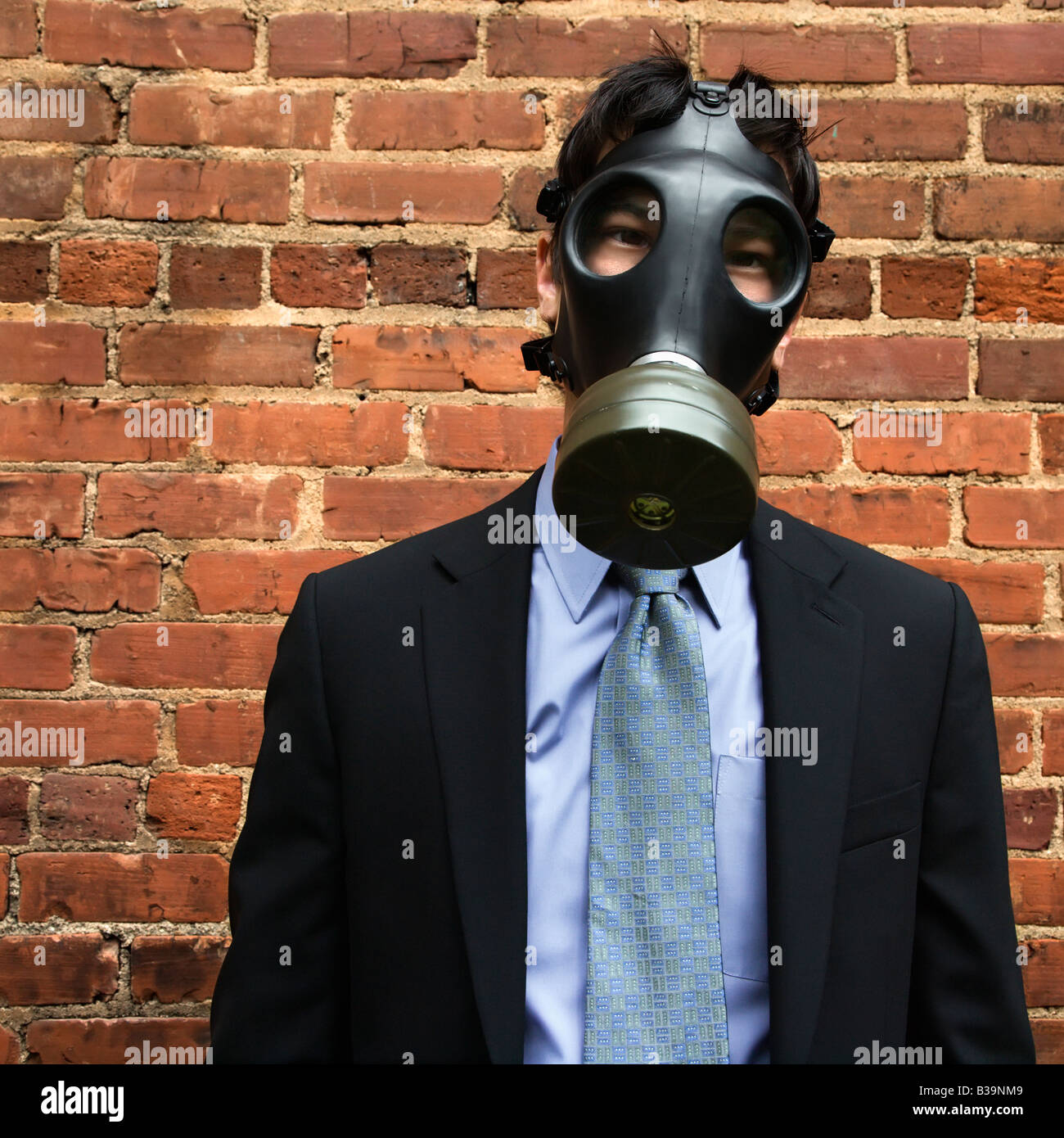 Businessman standing next to brick wall wearing gas mask Stock Photo ...