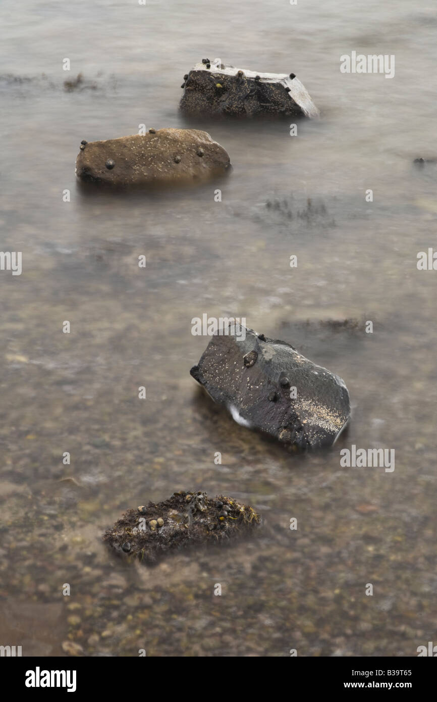 Water lapping around rocks on a beach on Lindisfarne (Holy Island) on ...