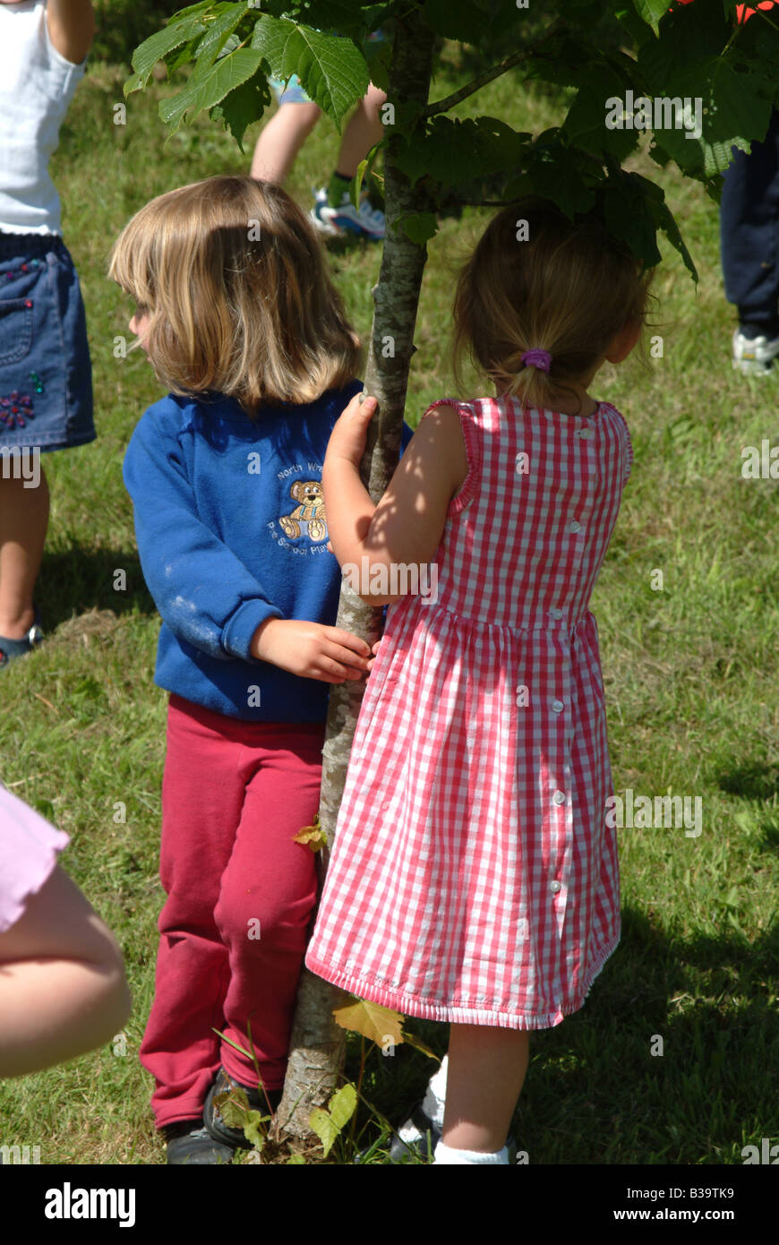 Nursery children playing next to a tree Stock Photo - Alamy