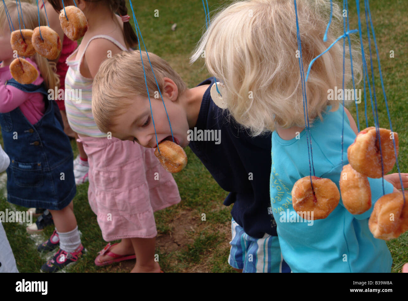 Children eating doughnuts off a string Stock Photo - Alamy
