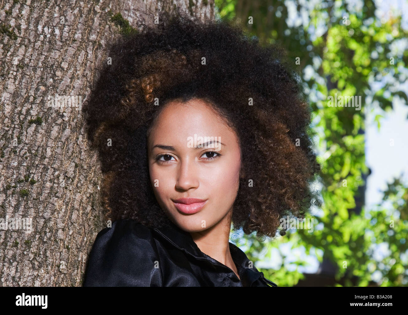 African woman leaning on tree Stock Photo - Alamy