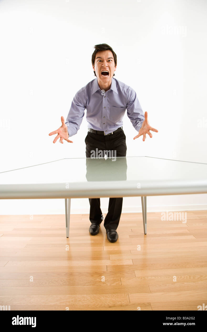 Young Asian business man standing at conference table yelling at unseen ...