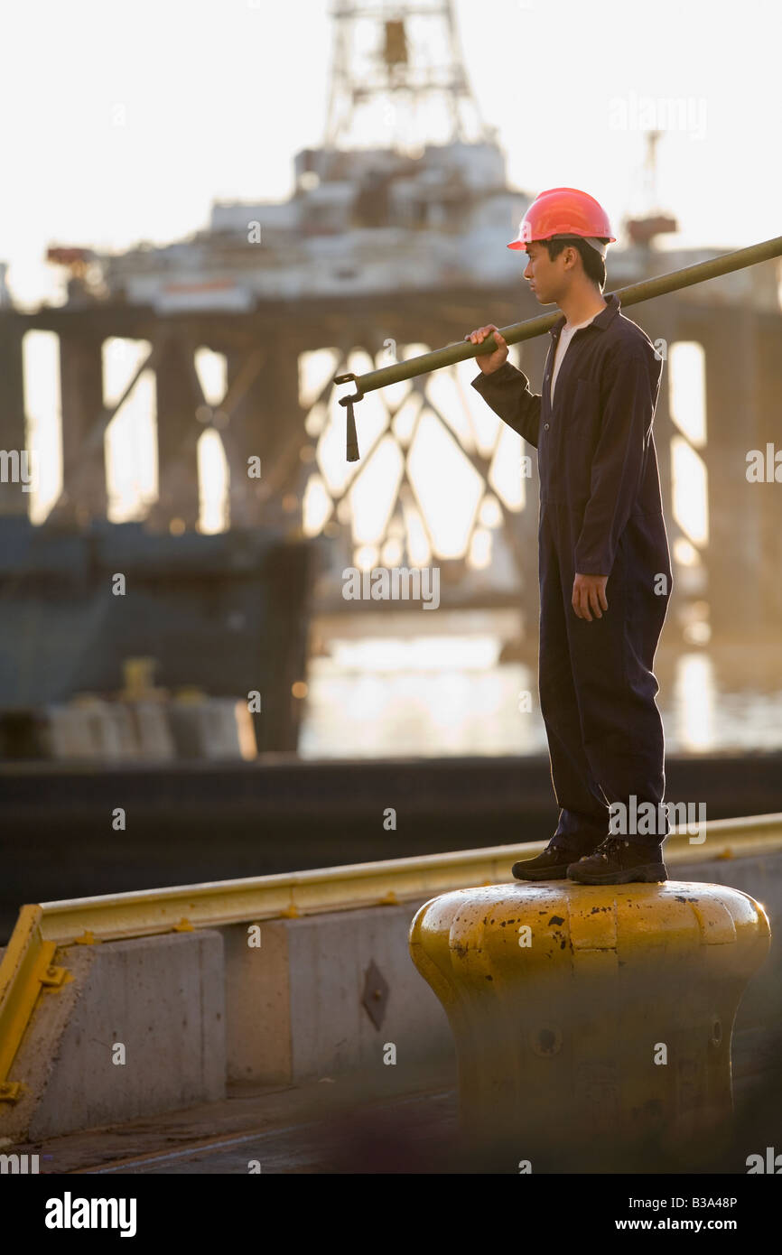Asian male dock worker holding pipe Stock Photo - Alamy