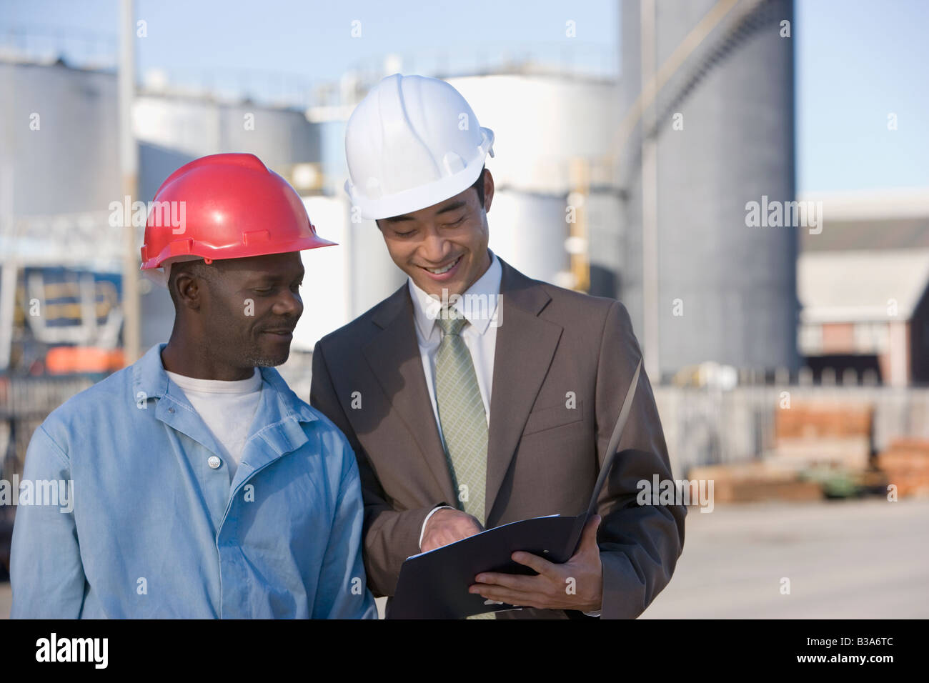 Multi-ethnic businessman and construction worker looking at paperwork ...