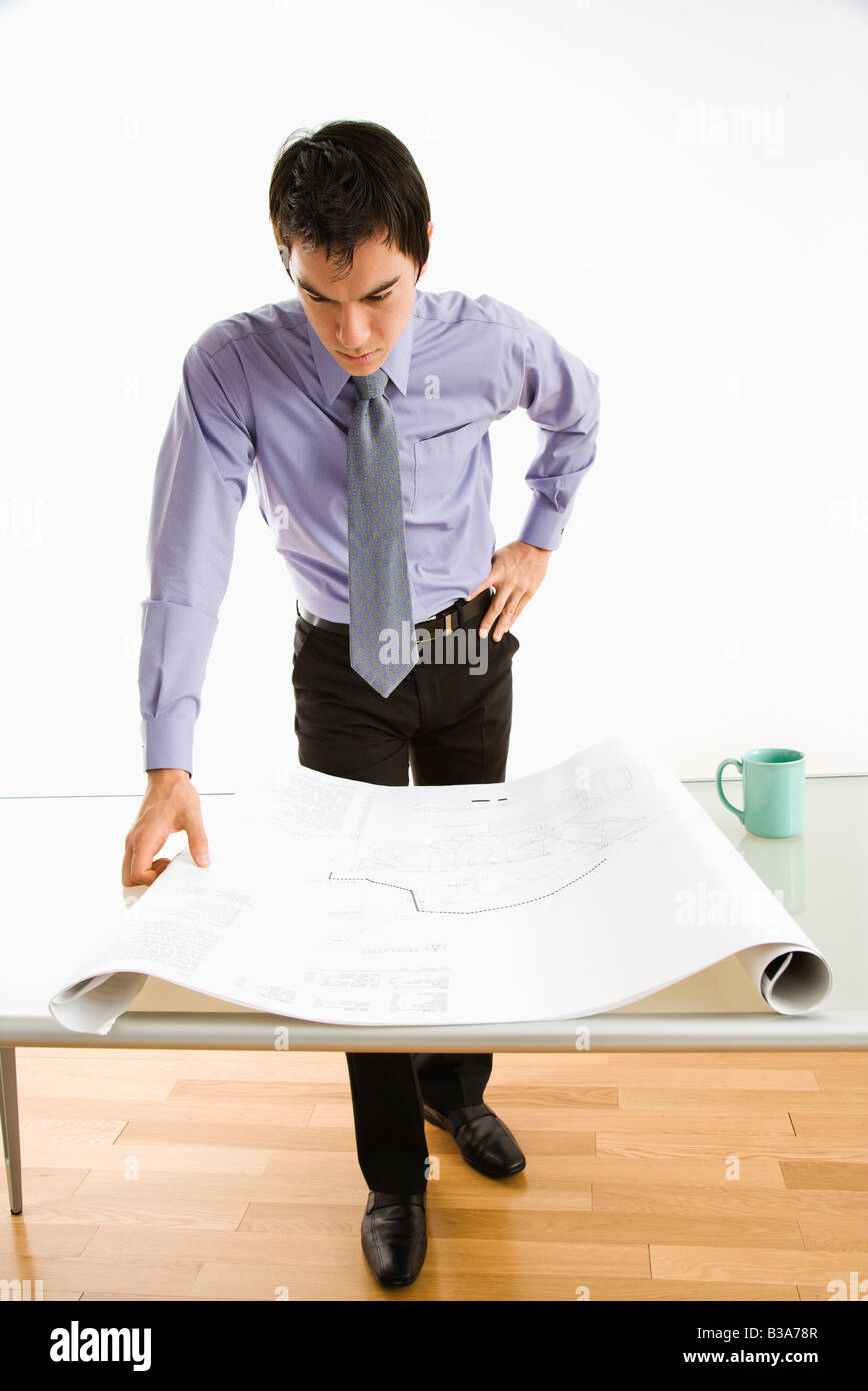 Asian business man standing looking over blueprints Stock Photo - Alamy