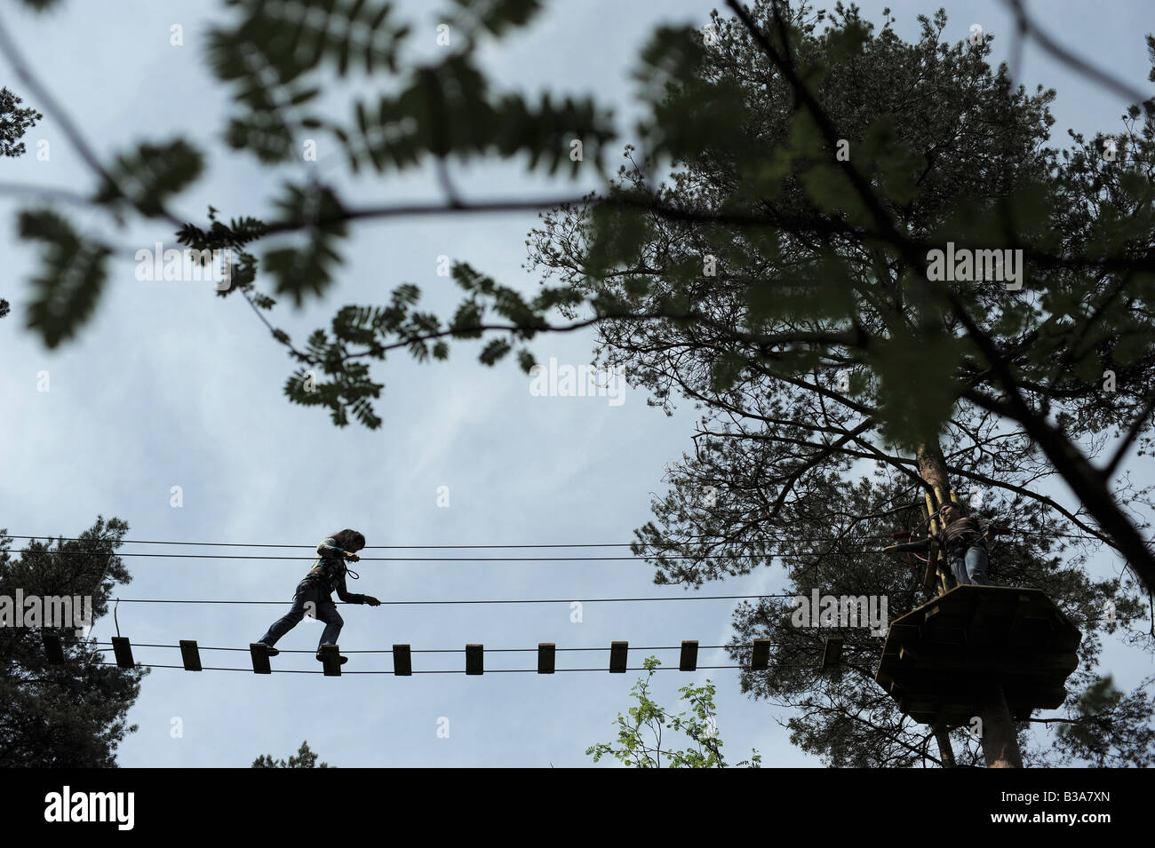 A woman walks and balances across a high rope bridge at Go Ape at ...