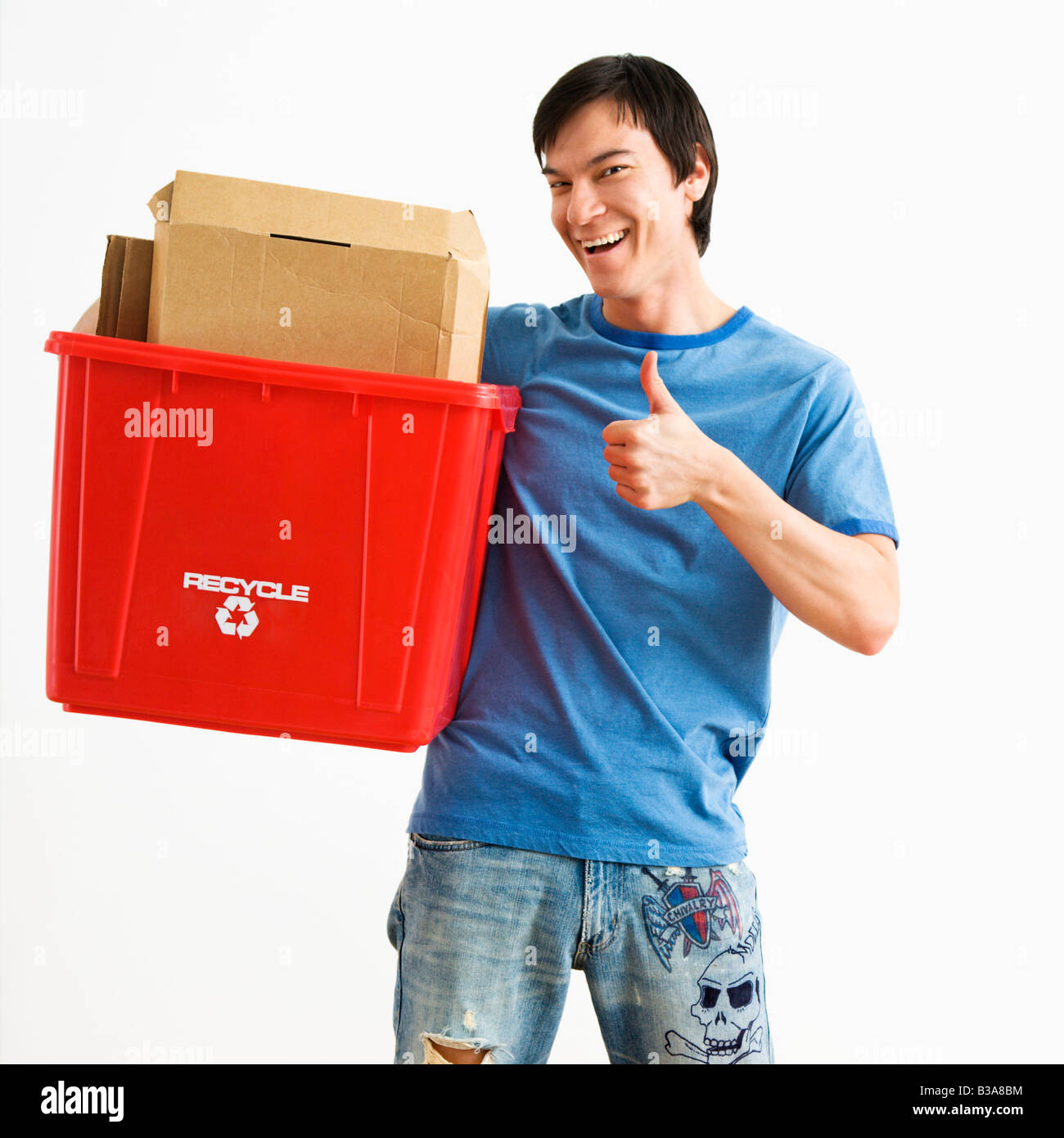 Portrait of smiling Asian young man standing holding recycling bin ...