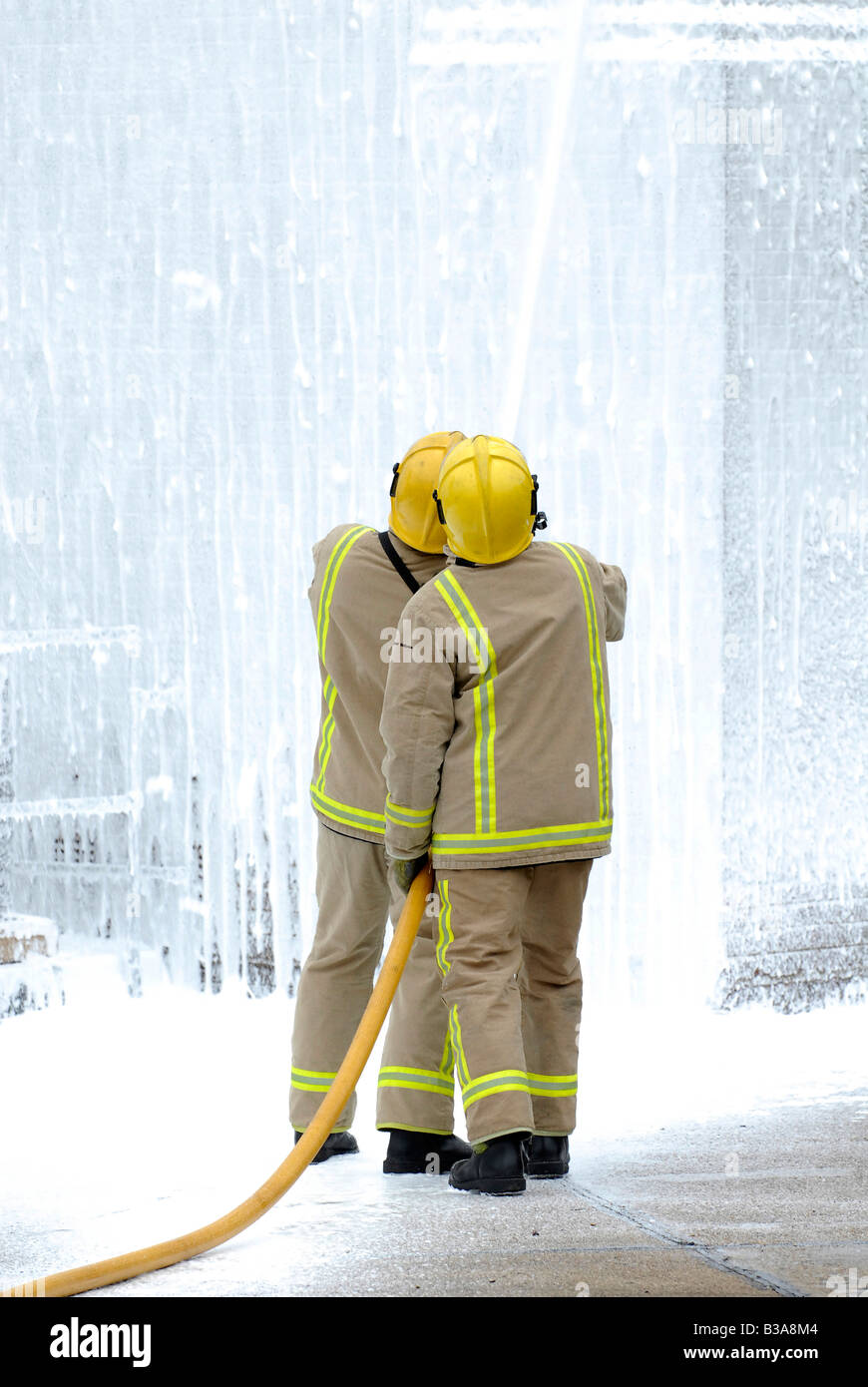 UK firefighters spraying fire-fighting foam onto a burning building ...