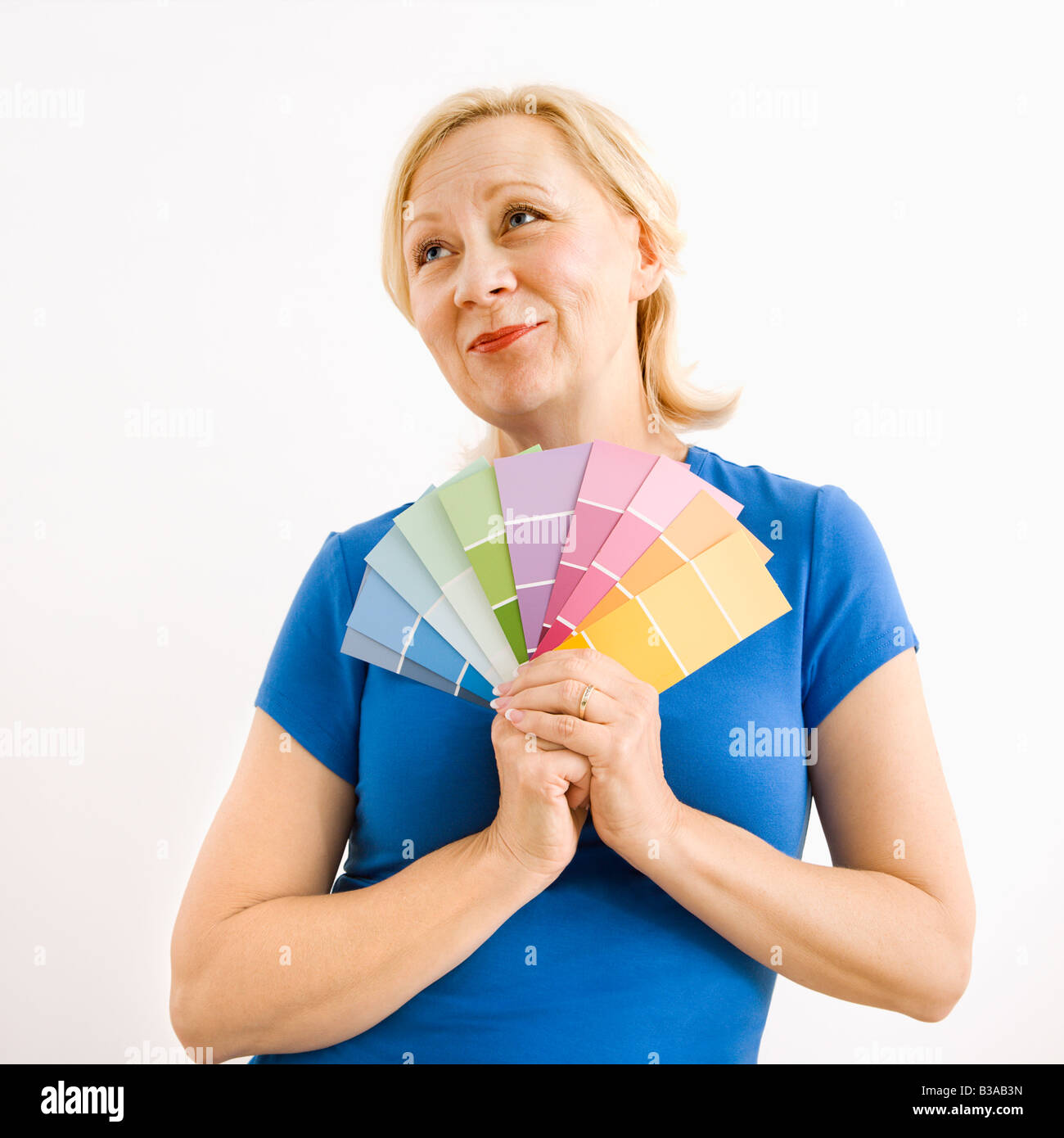 Portrait of smiling adult blonde woman holding paint swatches with ...