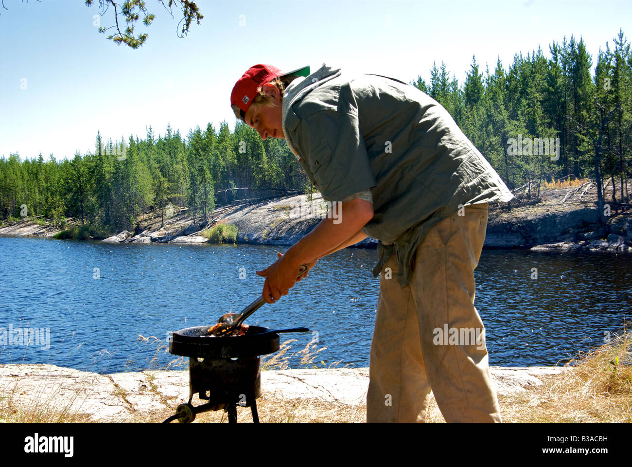Fishing guide deep frying fish fillets for shore lunch at lakeside camp ...
