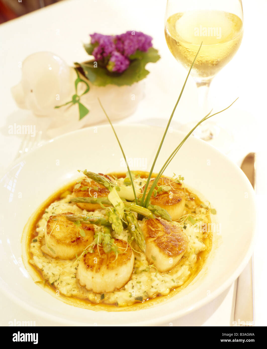 A meal of pan seared Scallops, risotto and a glass of wine Stock Photo ...