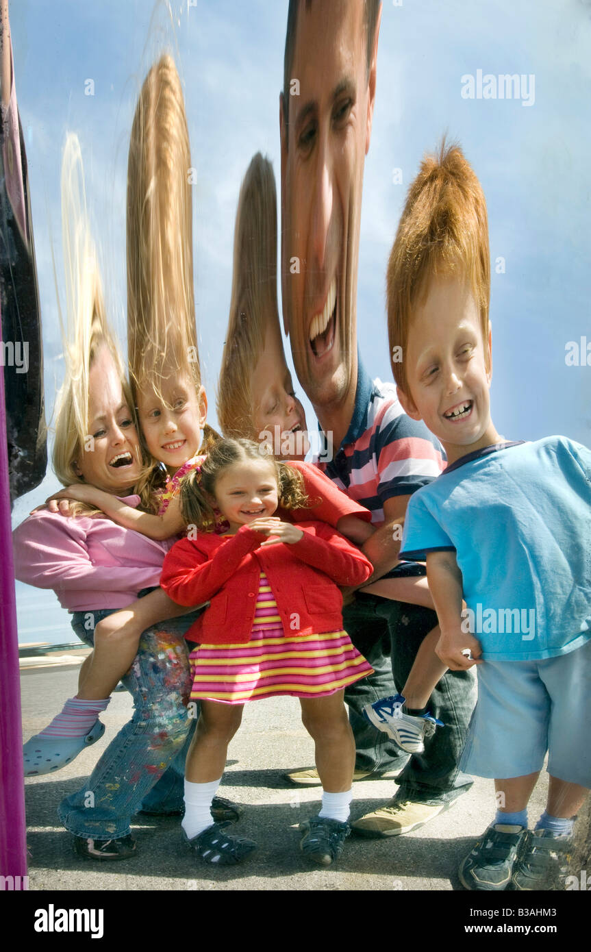 A family reflected in an old fairground mirror on the seafront at ...