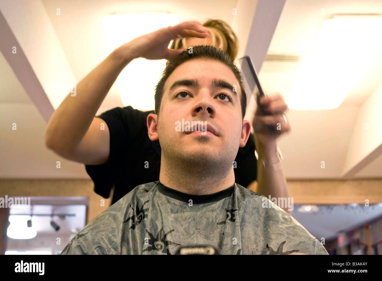 A young man getting his hair cut by a hairdresser at the salon Stock ...