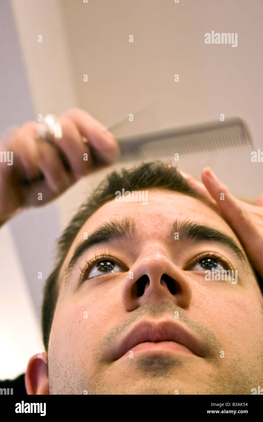 A young man getting his hair cut by a hairdresser at the salon Stock ...