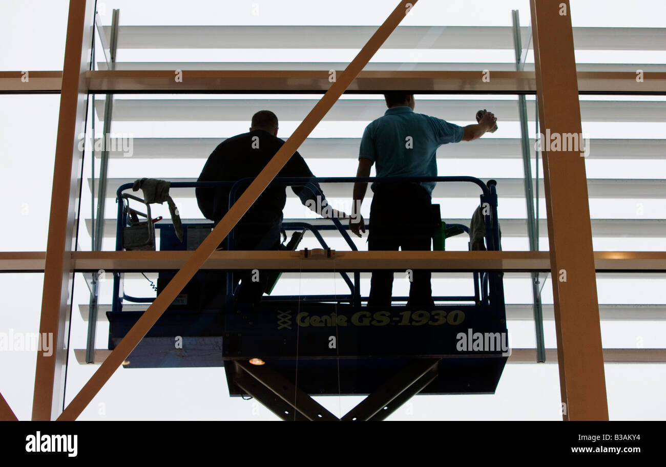 Two window cleaners cleaning a large window of an outlet store ...
