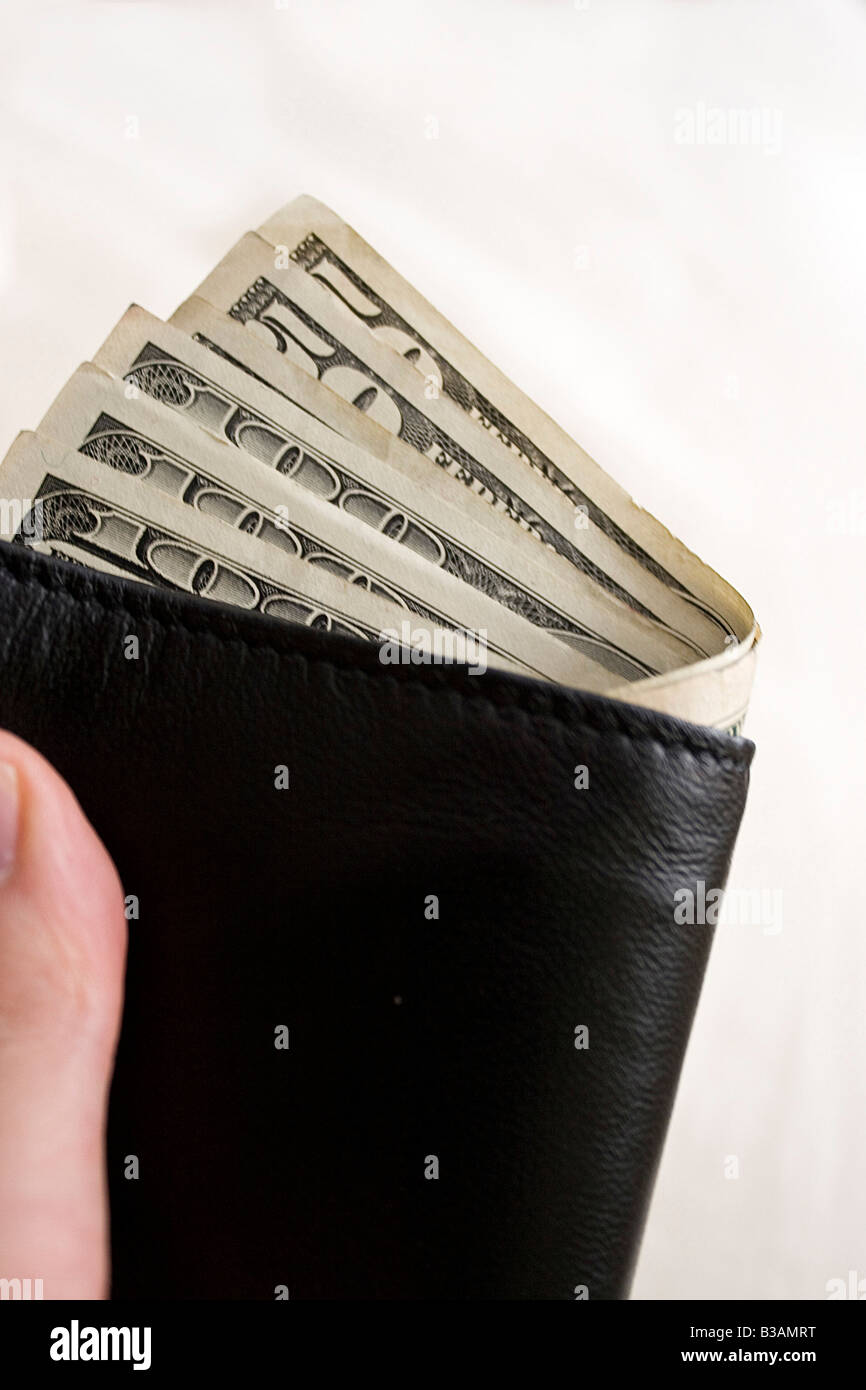 A hand holding a wallet full of cash isolated over a gold background ...