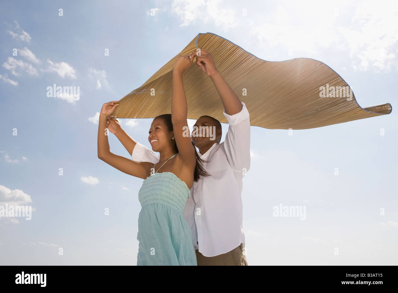 African couple holding mat in wind Stock Photo - Alamy