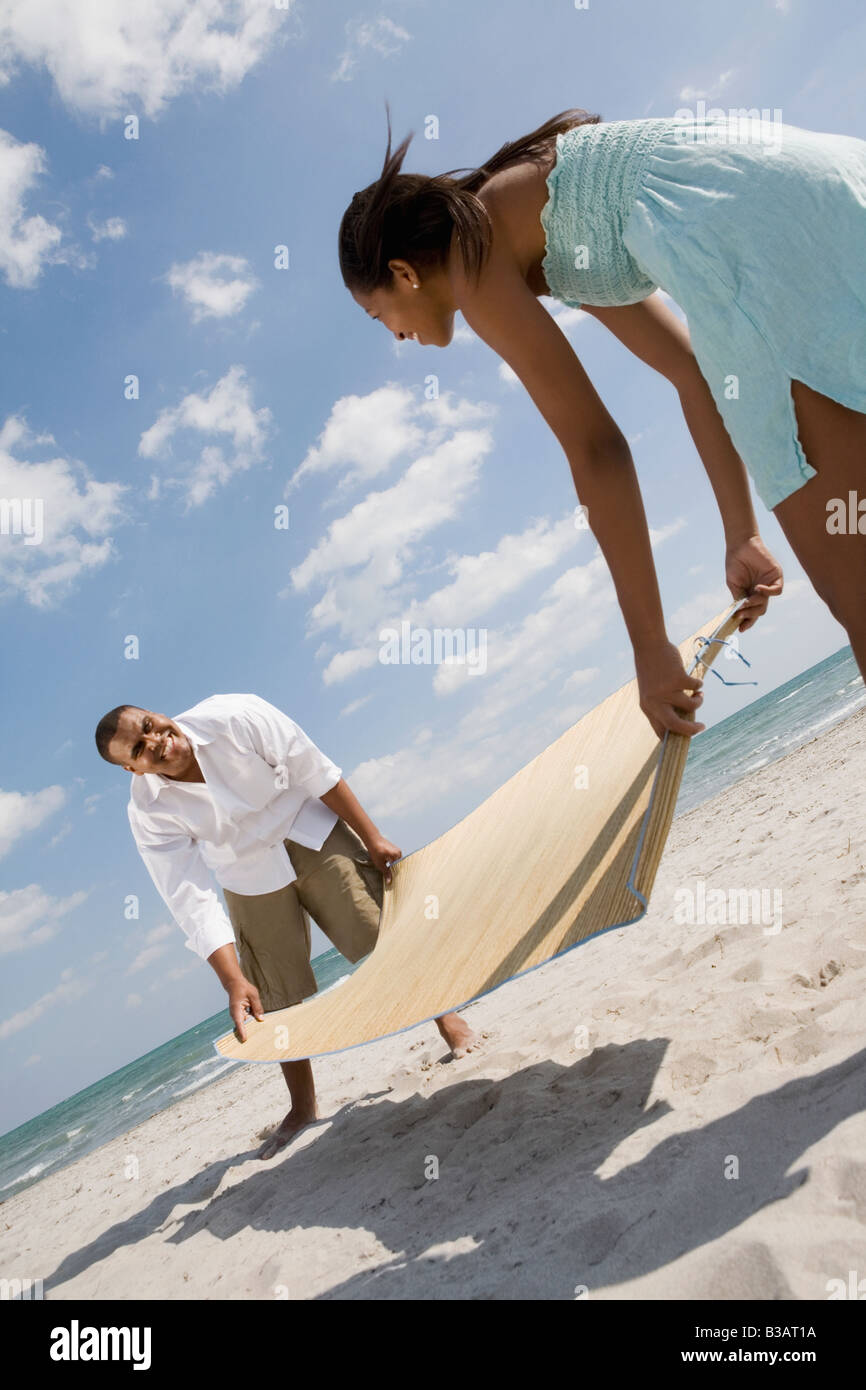 African couple laying mat on sand Stock Photo - Alamy
