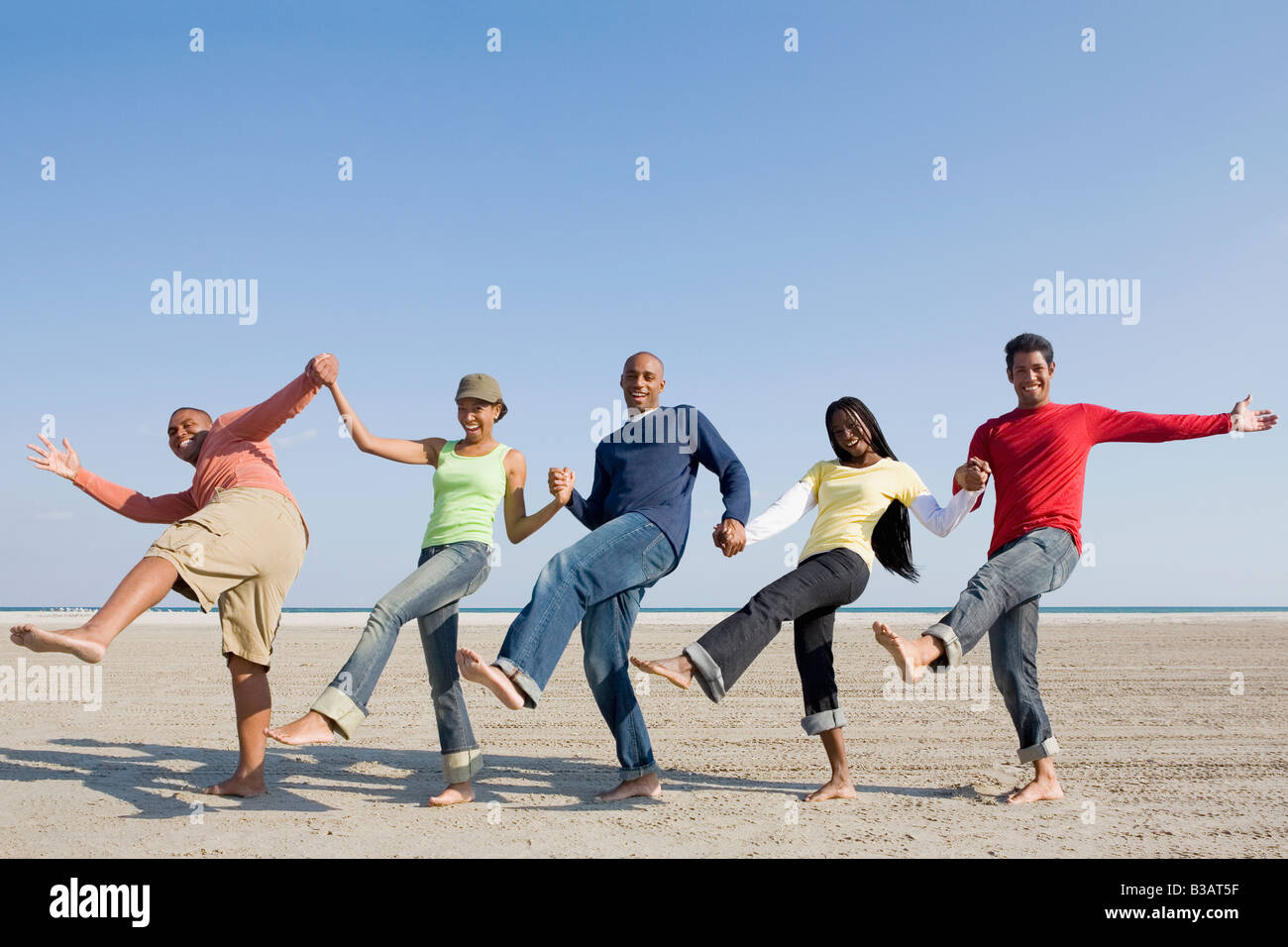 Multi-ethnic friends holding hands and kicking Stock Photo - Alamy