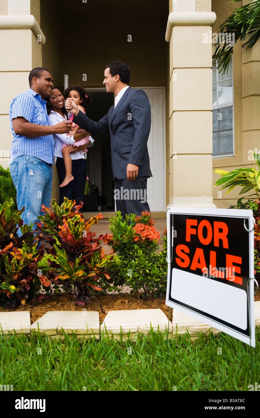 Hispanic real estate agent giving house keys to African family Stock ...