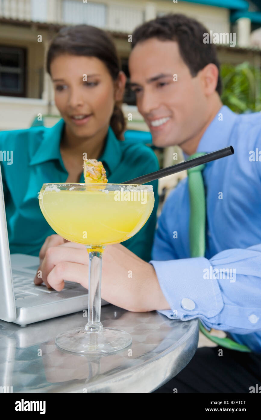 Cocktail in front of Hispanic couple looking at laptop Stock Photo - Alamy