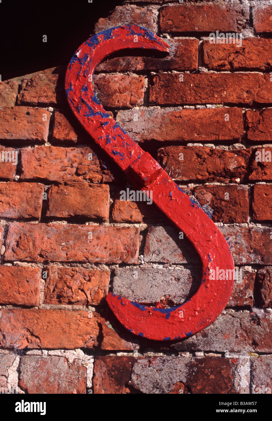 S-shaped reinforcing rod end supporting old red brick wall of a barn ...