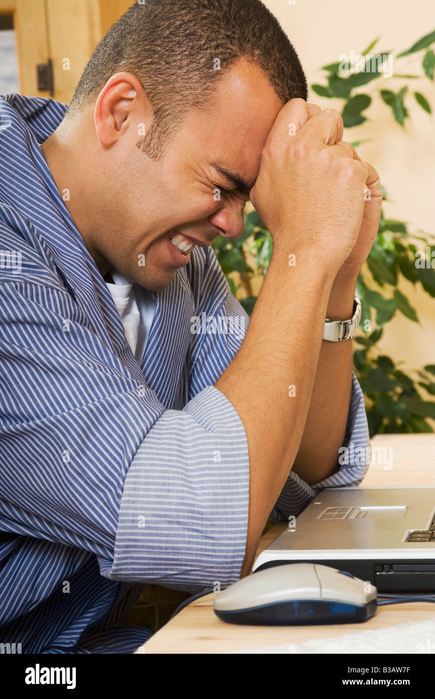 Frustrated Pacific Islander man next to laptop Stock Photo - Alamy