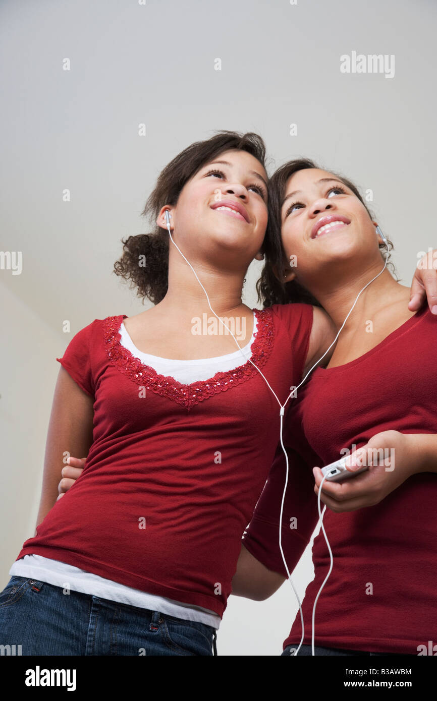 African twin sisters listening to same mp3 player Stock Photo - Alamy