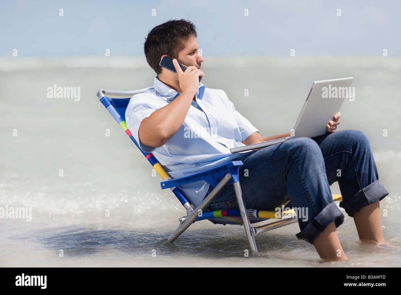 Hispanic man in beach chair with laptop Stock Photo - Alamy