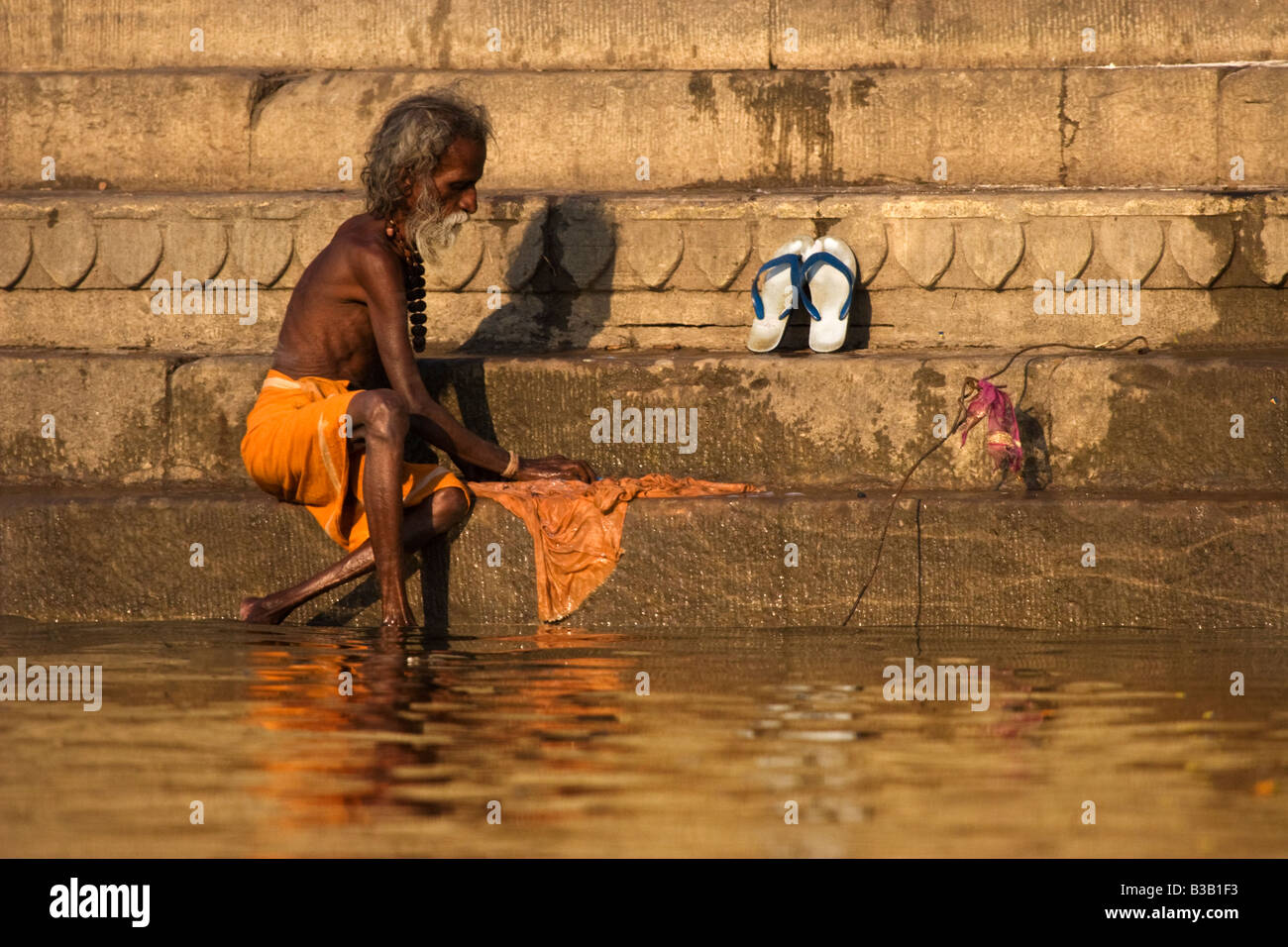 Indian man washing clothes in Varanasi on ghats of river Ganges in ...