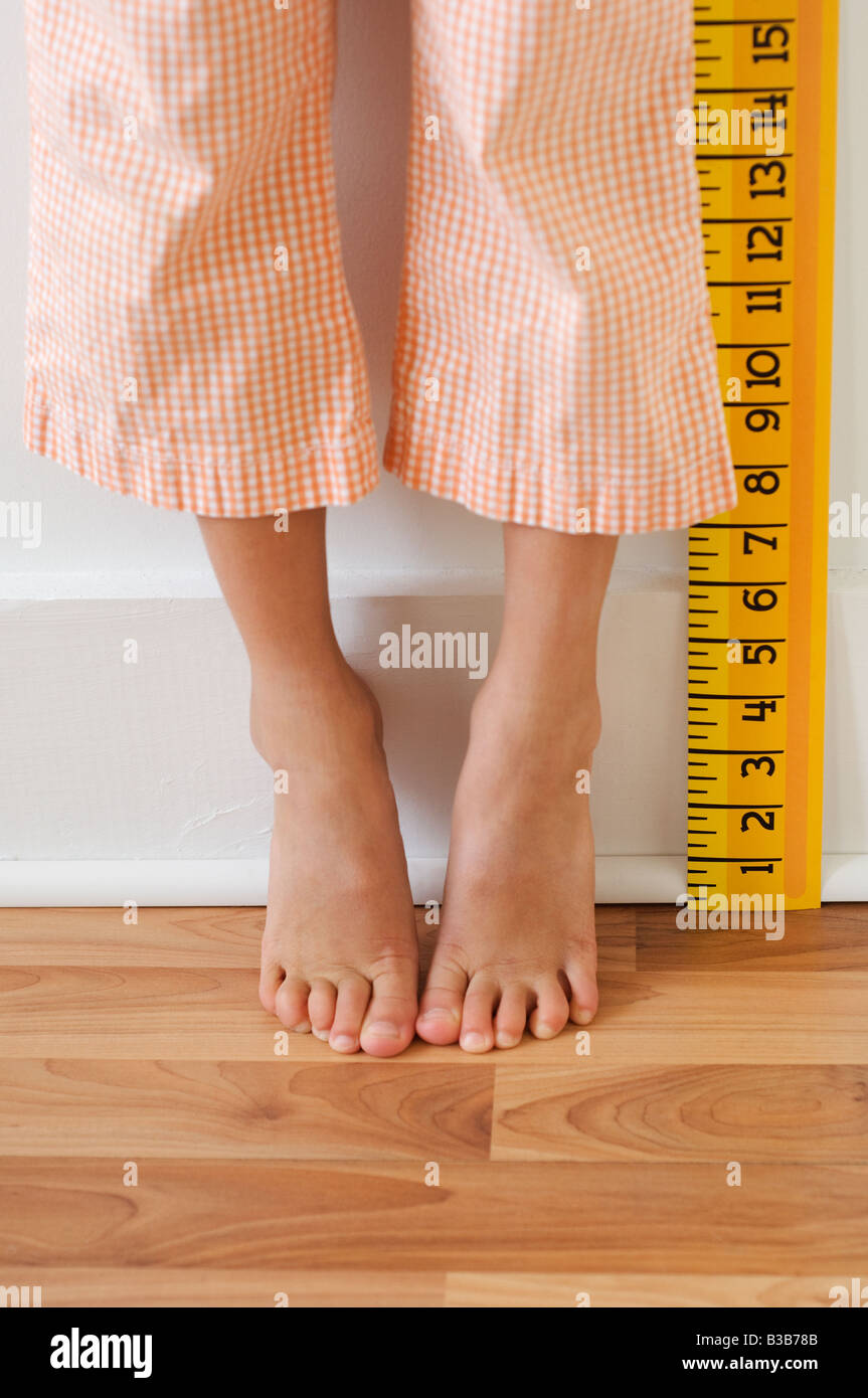 Girl standing on tiptoes next to ruler Stock Photo - Alamy