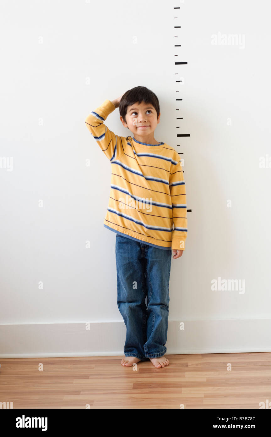 Asian boy standing next to height markers on wall Stock Photo - Alamy