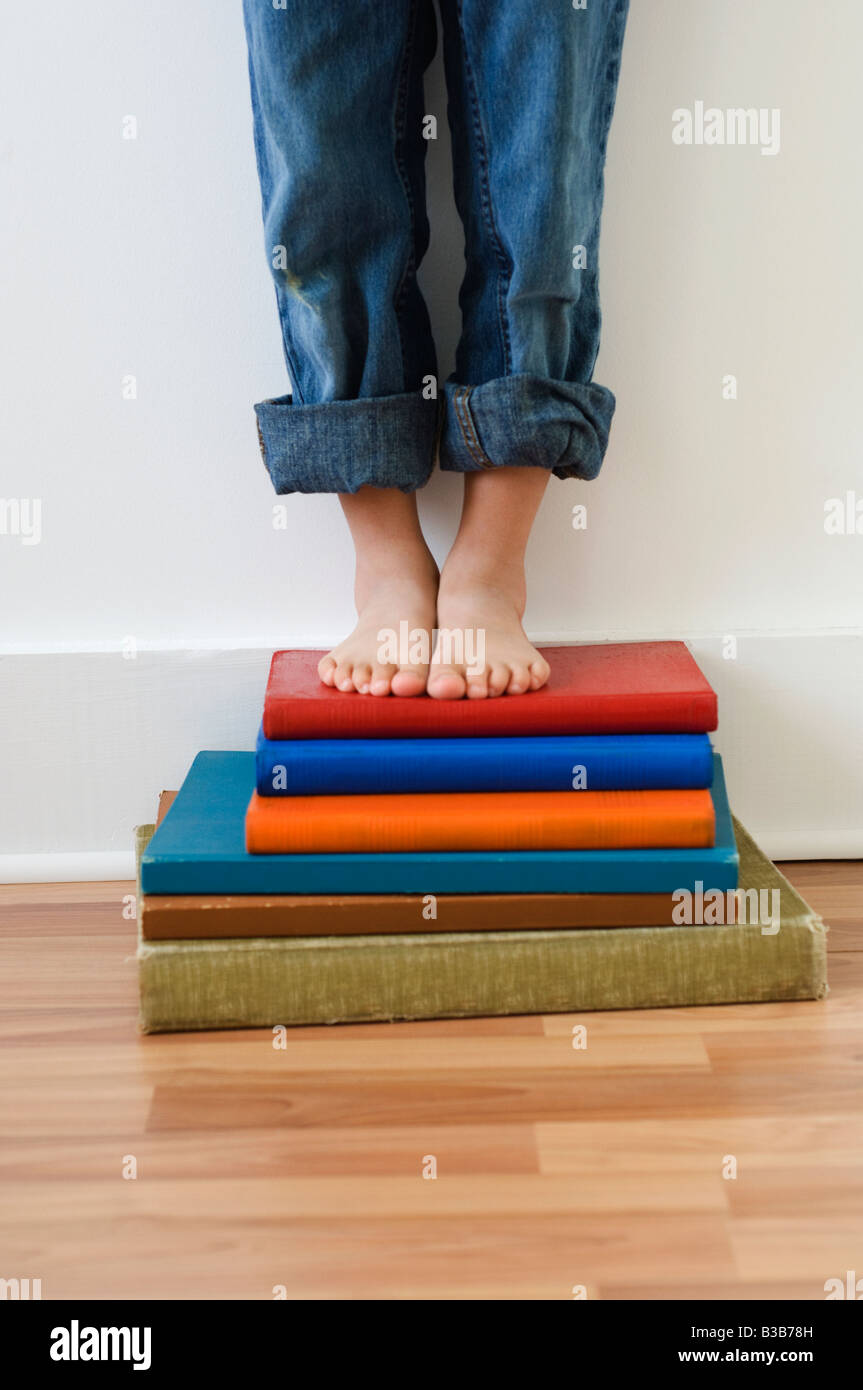 Boy standing on stack of books Stock Photo - Alamy